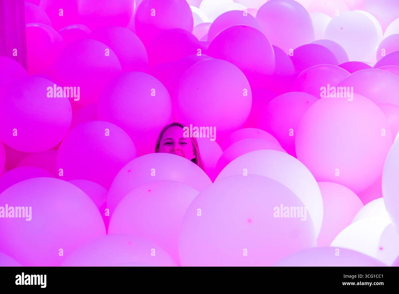 A playful scene featuring a person amidst a sea of pink and white ...