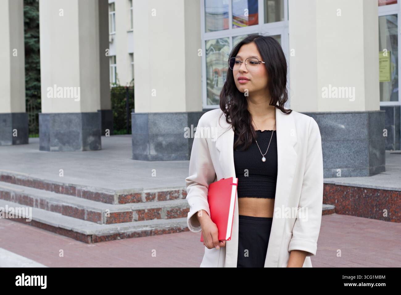 Young Indian college student standing with books near modern campus ...