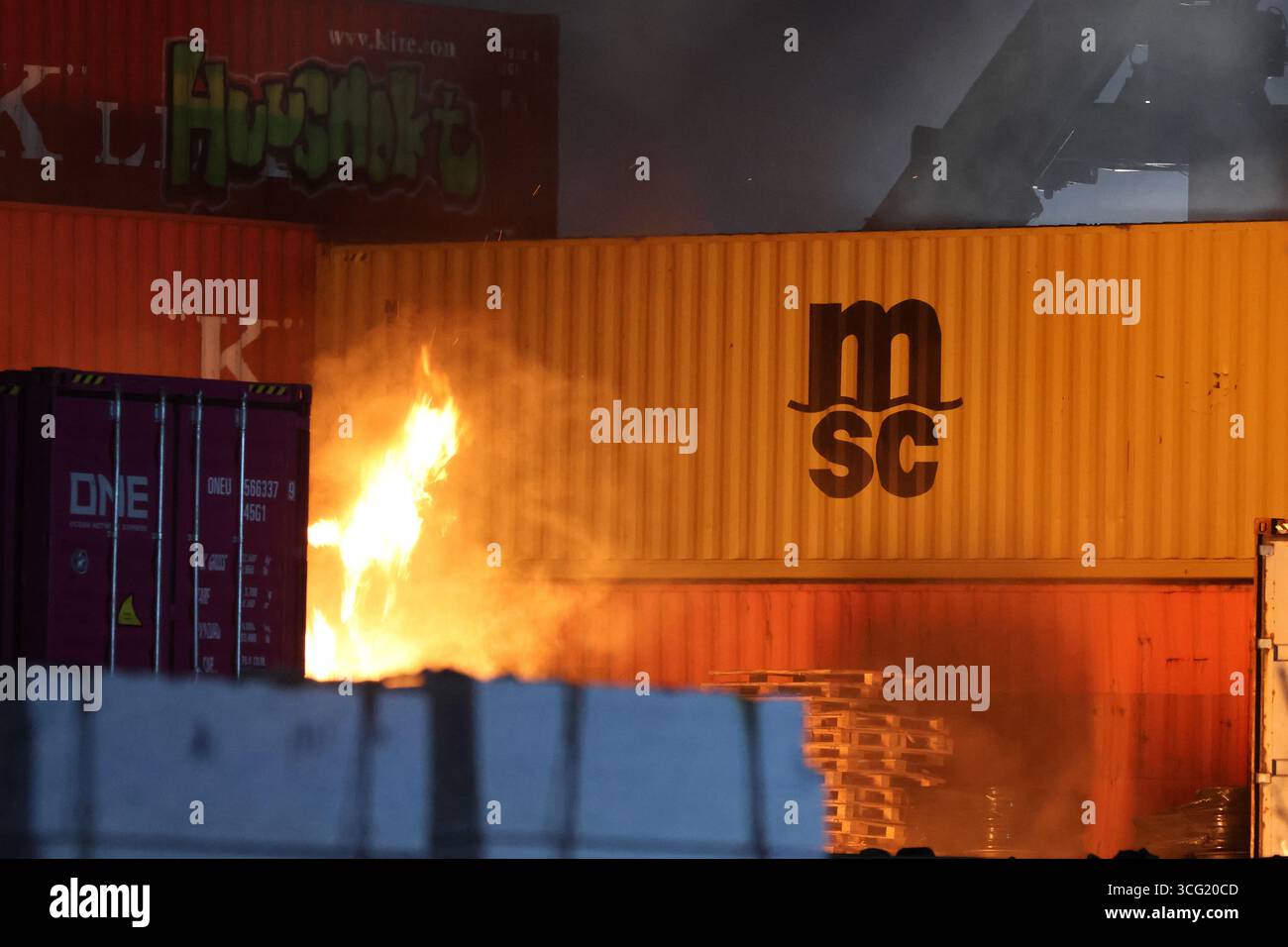 25 August 2025, Hamburg: The glow of fire can be seen during a fire in ...
