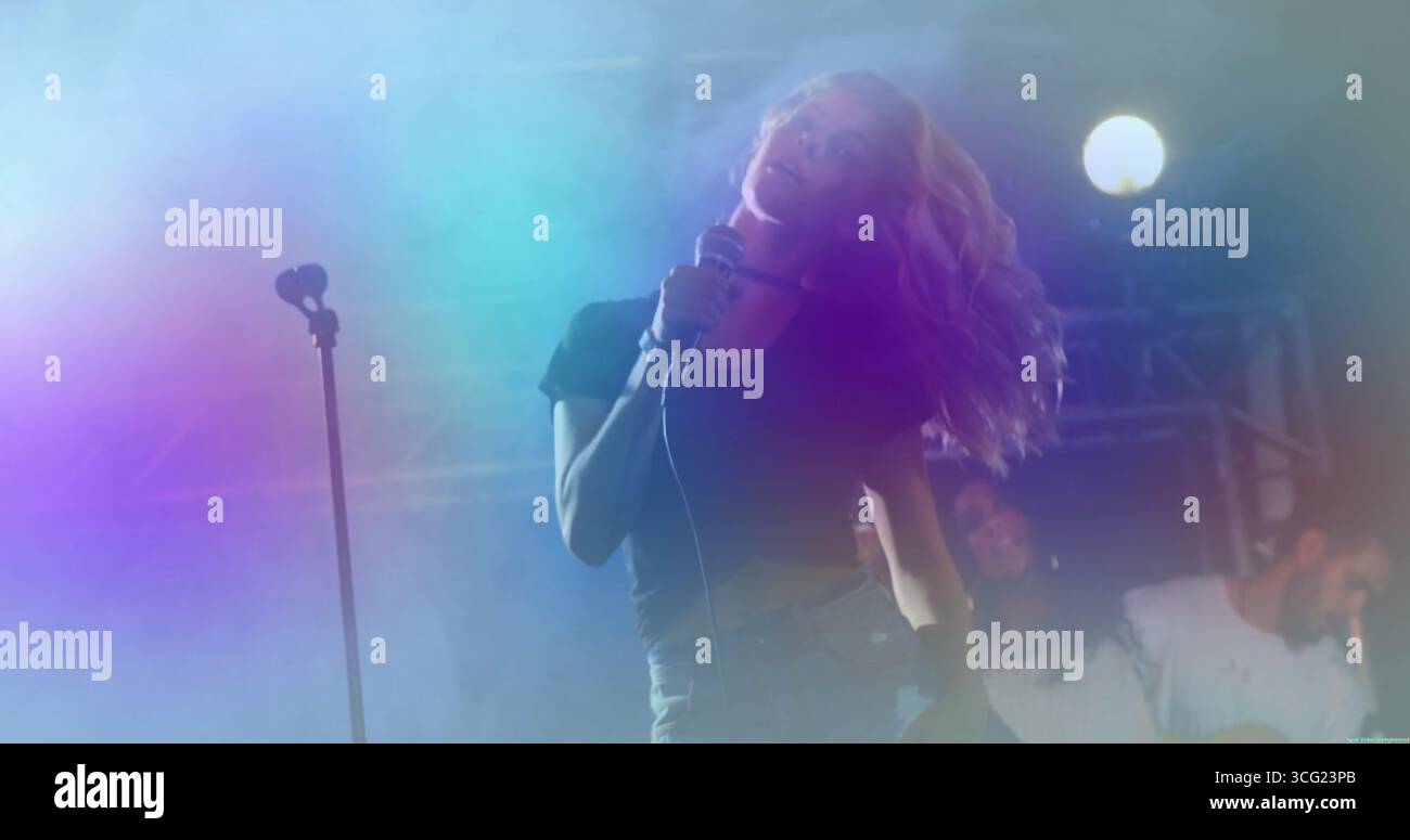 Performing female singer holding handheld microphone on concert stage ...