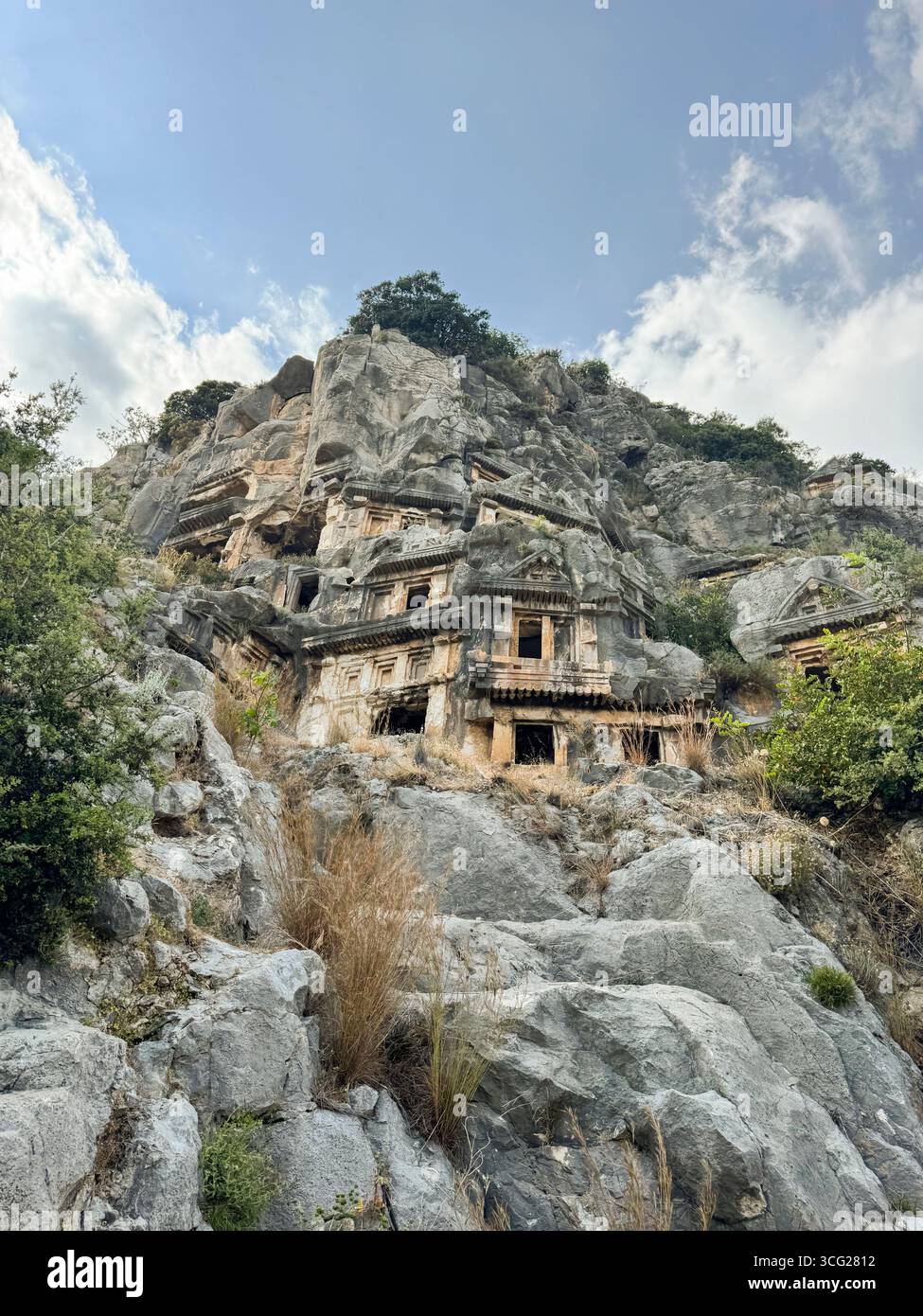 Historic rock-cut temples are visible on a steep mountainside ...