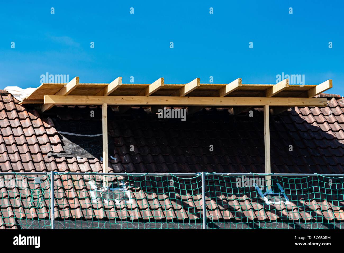 A wooden framework is being constructed on a slanted roof at a ...