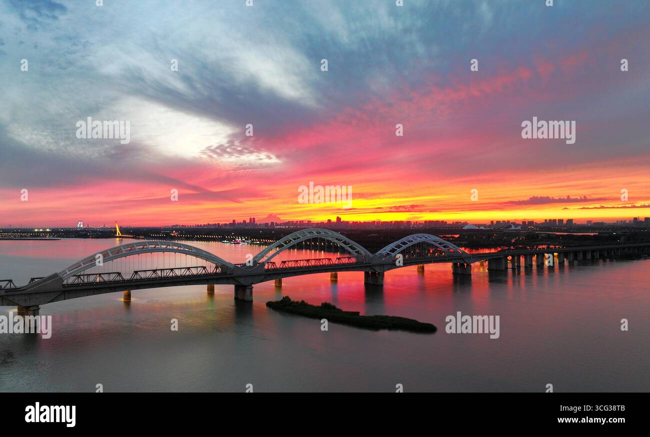 Sunset illuminates the sky over the Songhua River in Harbin City ...