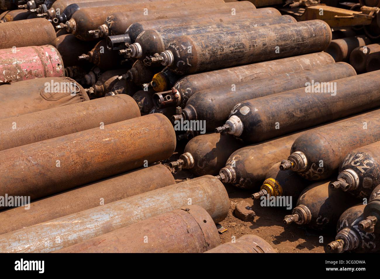 This image displays a pile of old, rusty industrial gas cylinders ...
