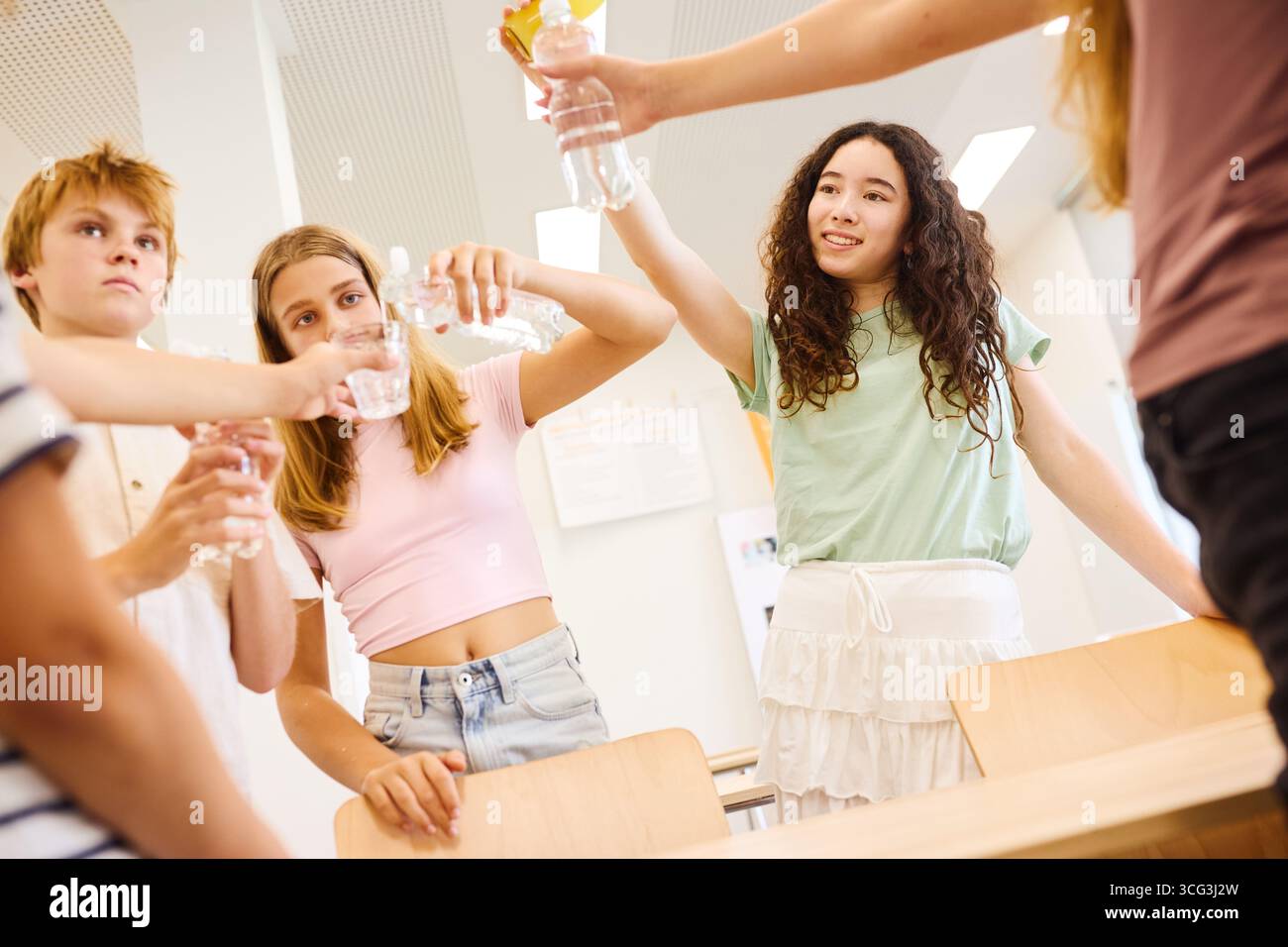 Students gathered in a school cafeteria sharing a friendly moment with ...