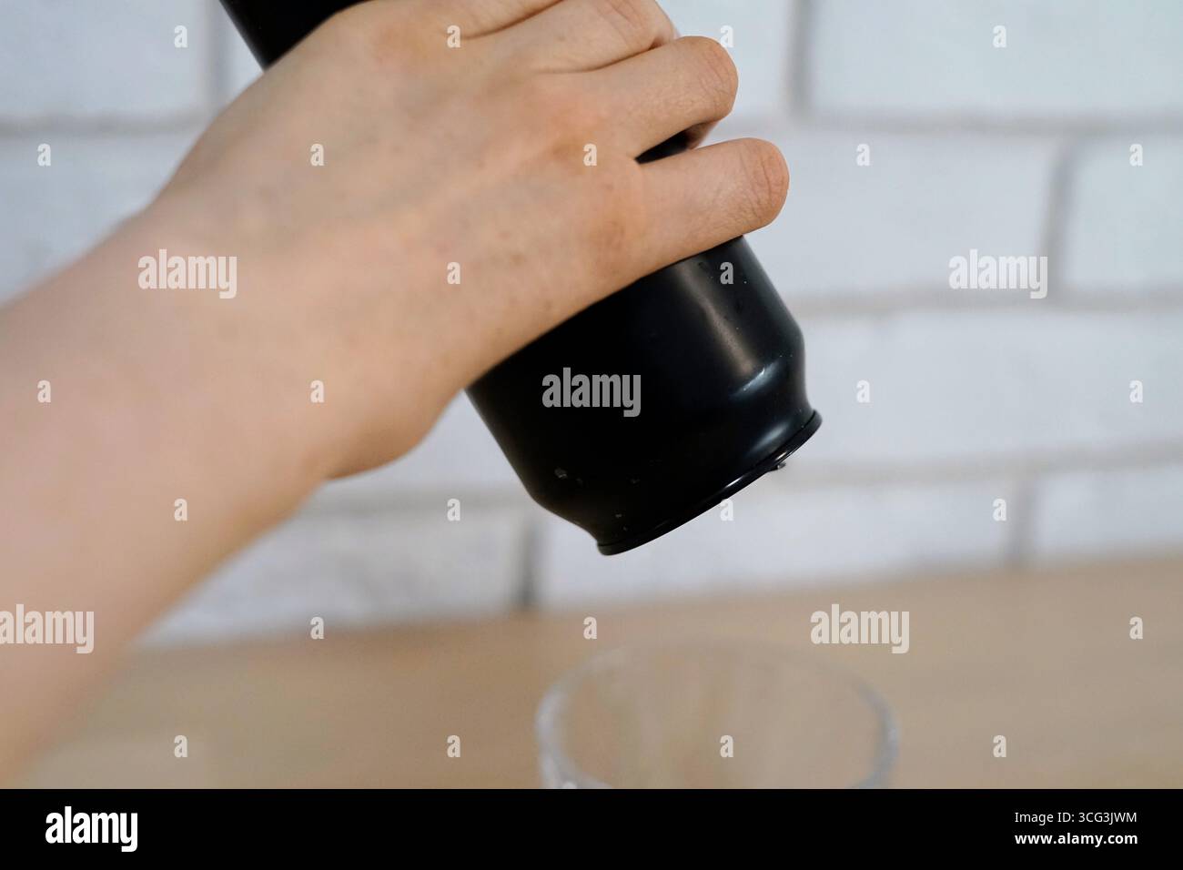 A hand is shaking a bottle of black spice over a glass dish Stock Photo ...