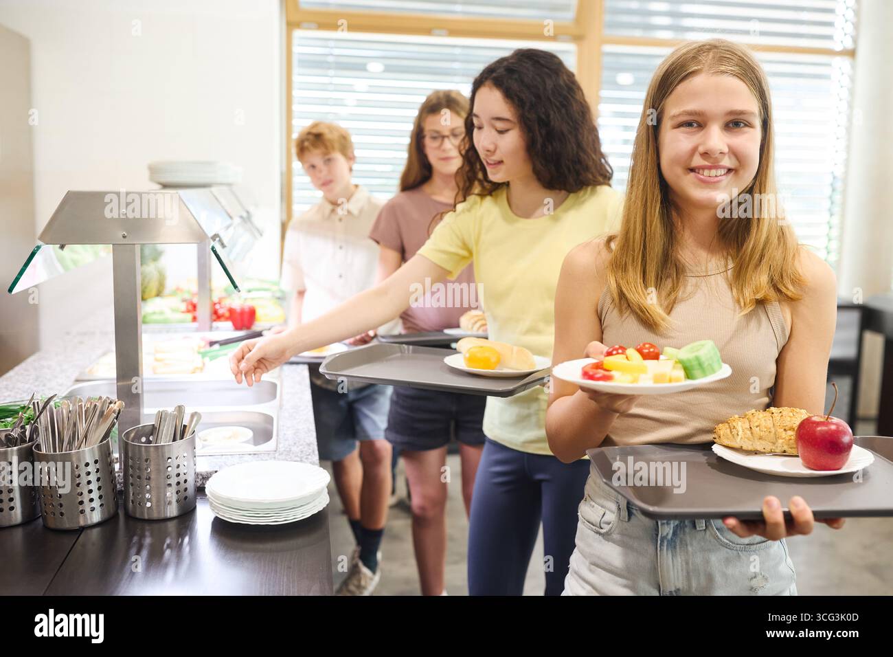 A diverse group of students selects nutritious food options at a school ...