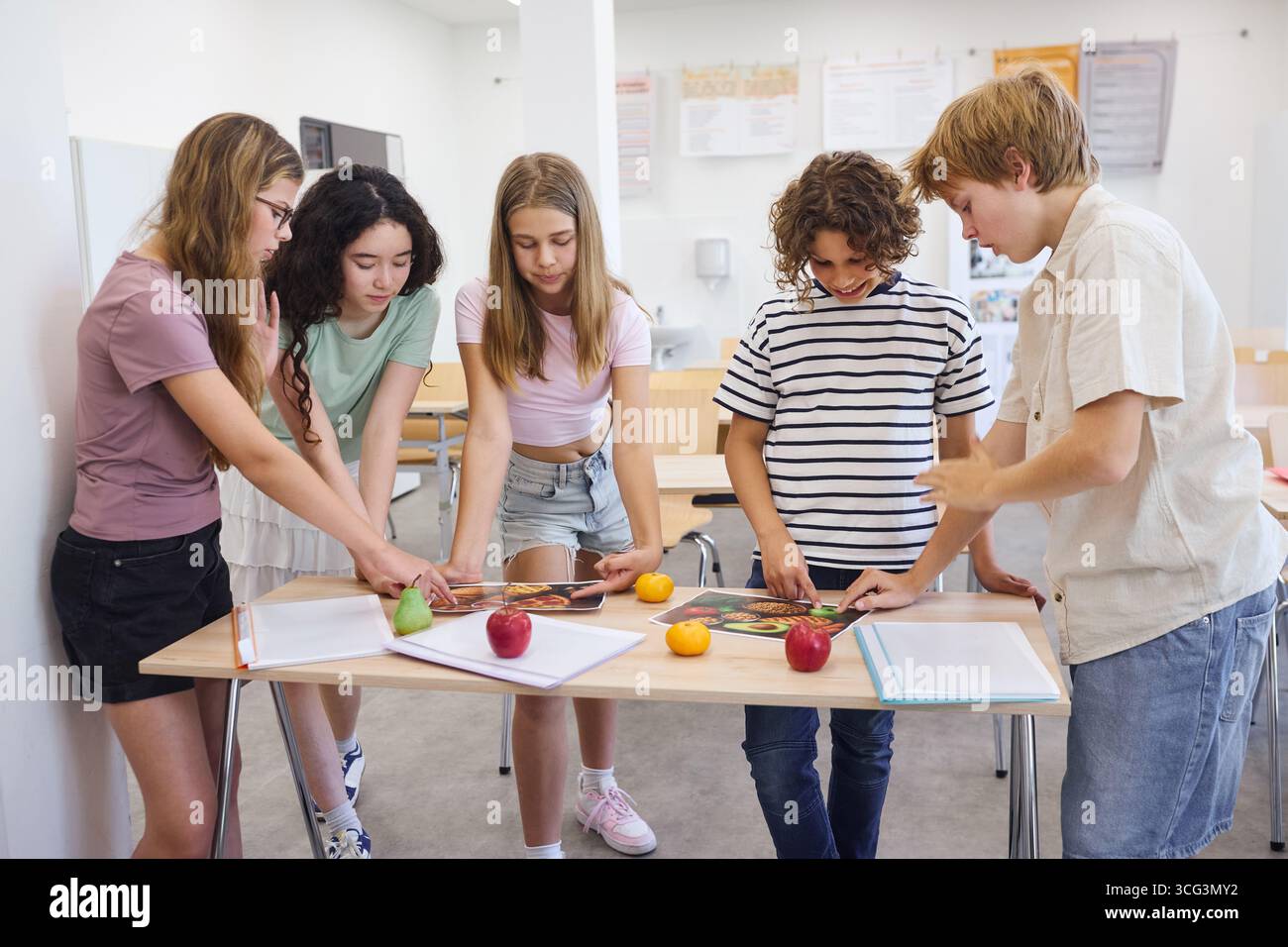 A group of teenagers working together in a classroom setting, engaging in interactive ...