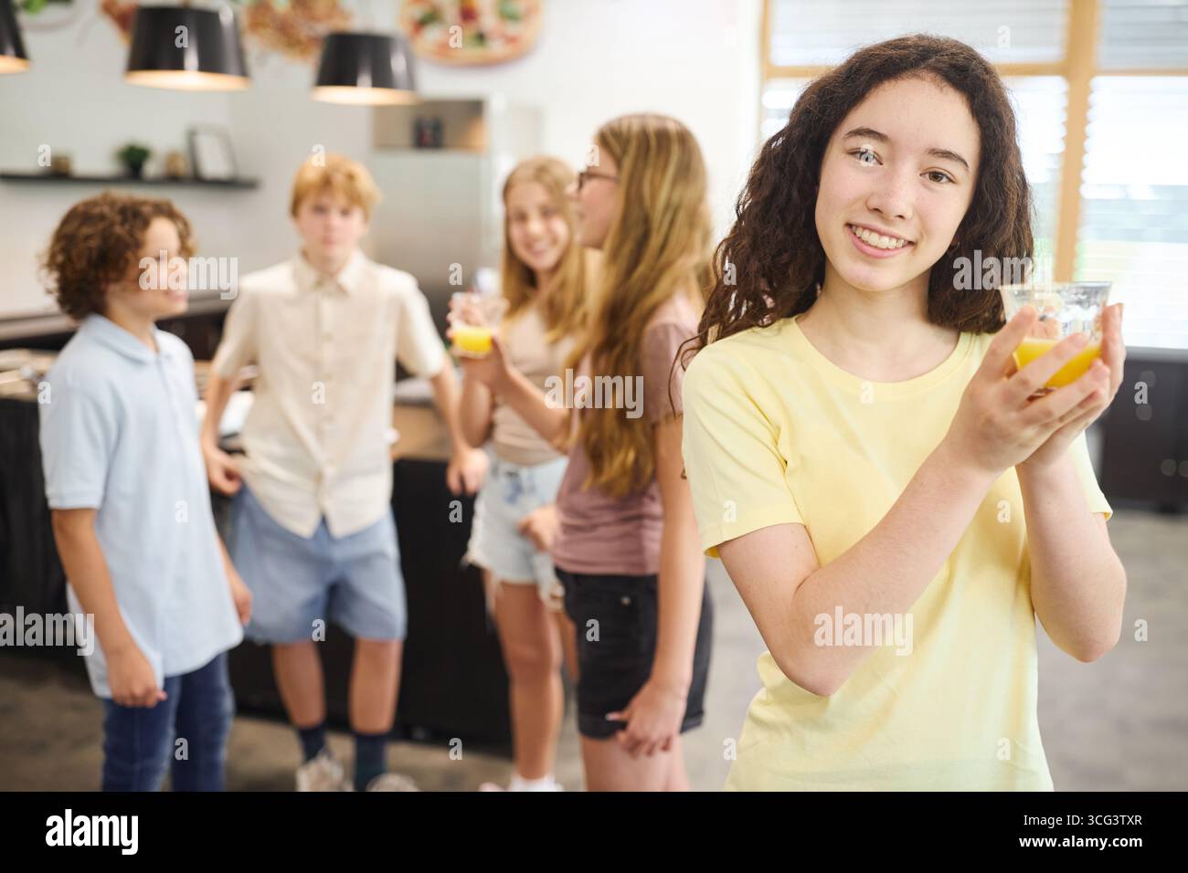 Teenagers socialize in a modern school cafeteria setting, holding ...