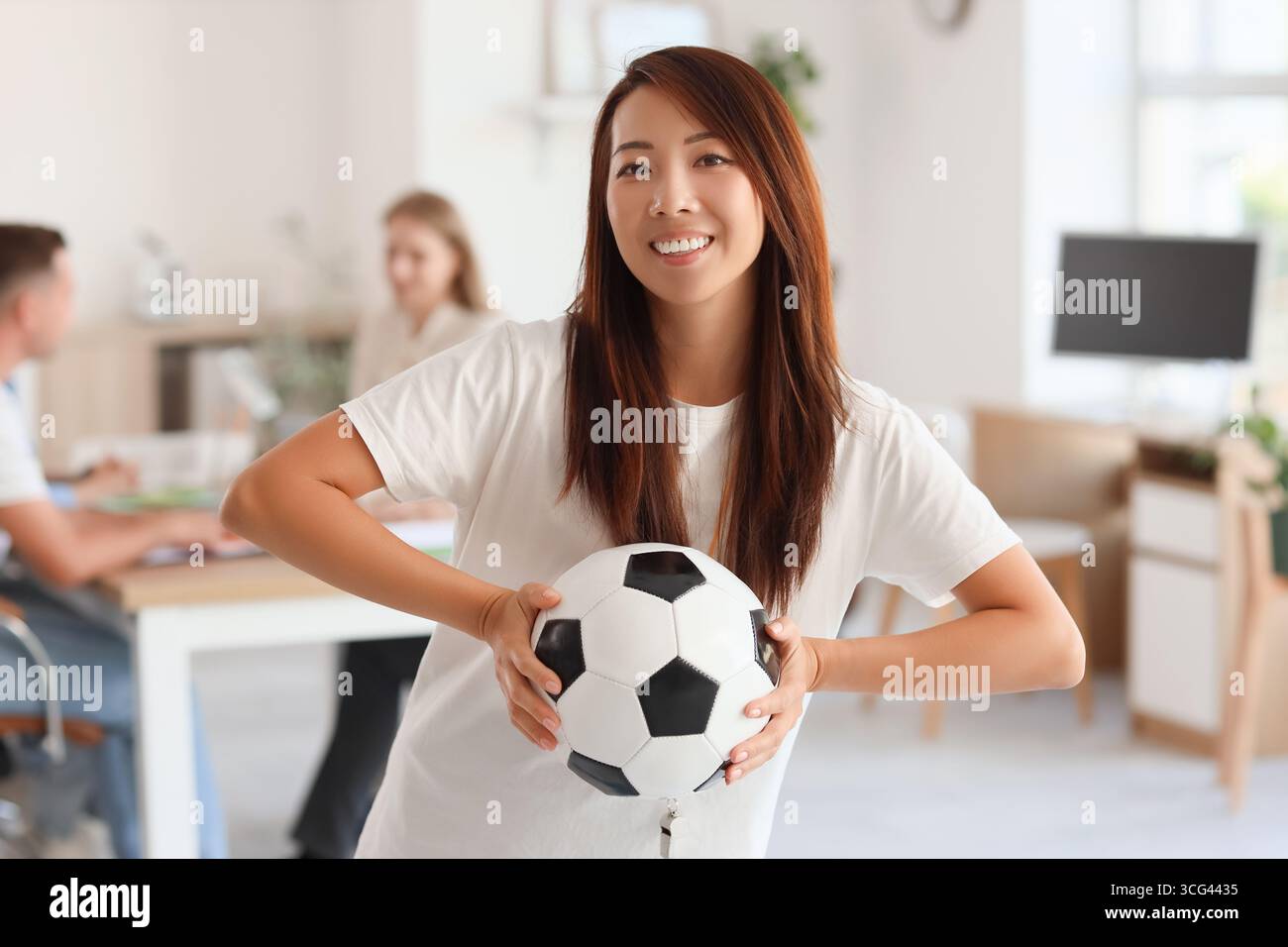 Female Asian PE teacher with soccer ball in school office Stock Photo ...