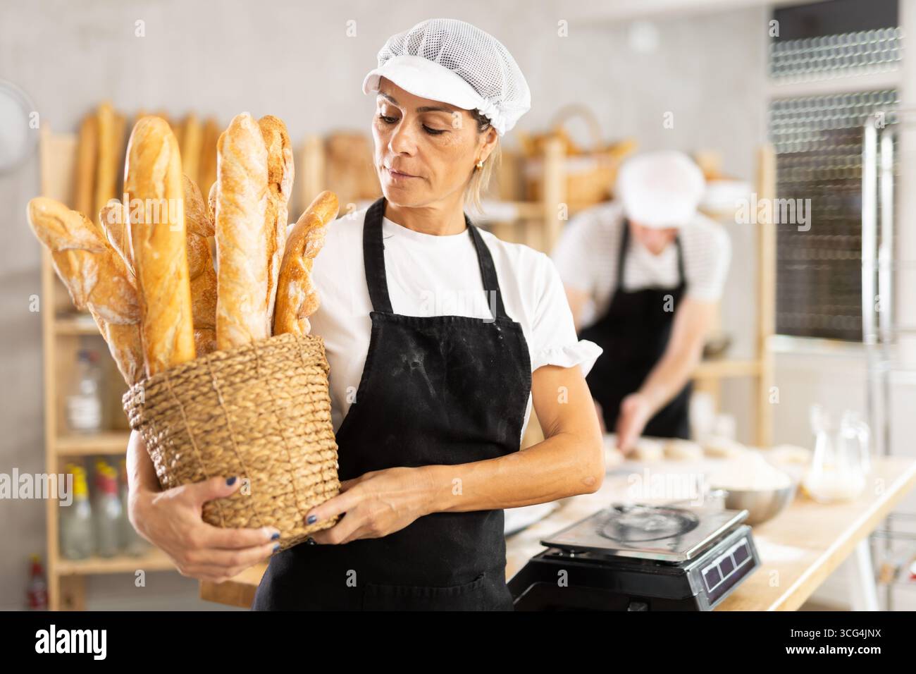Female baker with basket of aromatic baguettes in bakery Stock Photo ...