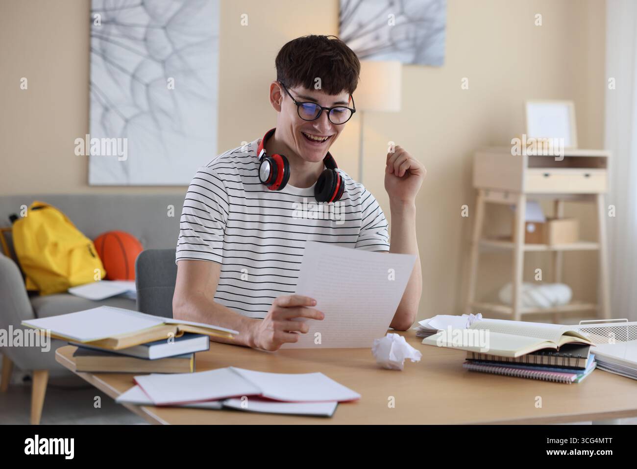 Happy student celebrating good exam result at table indoors Stock Photo ...