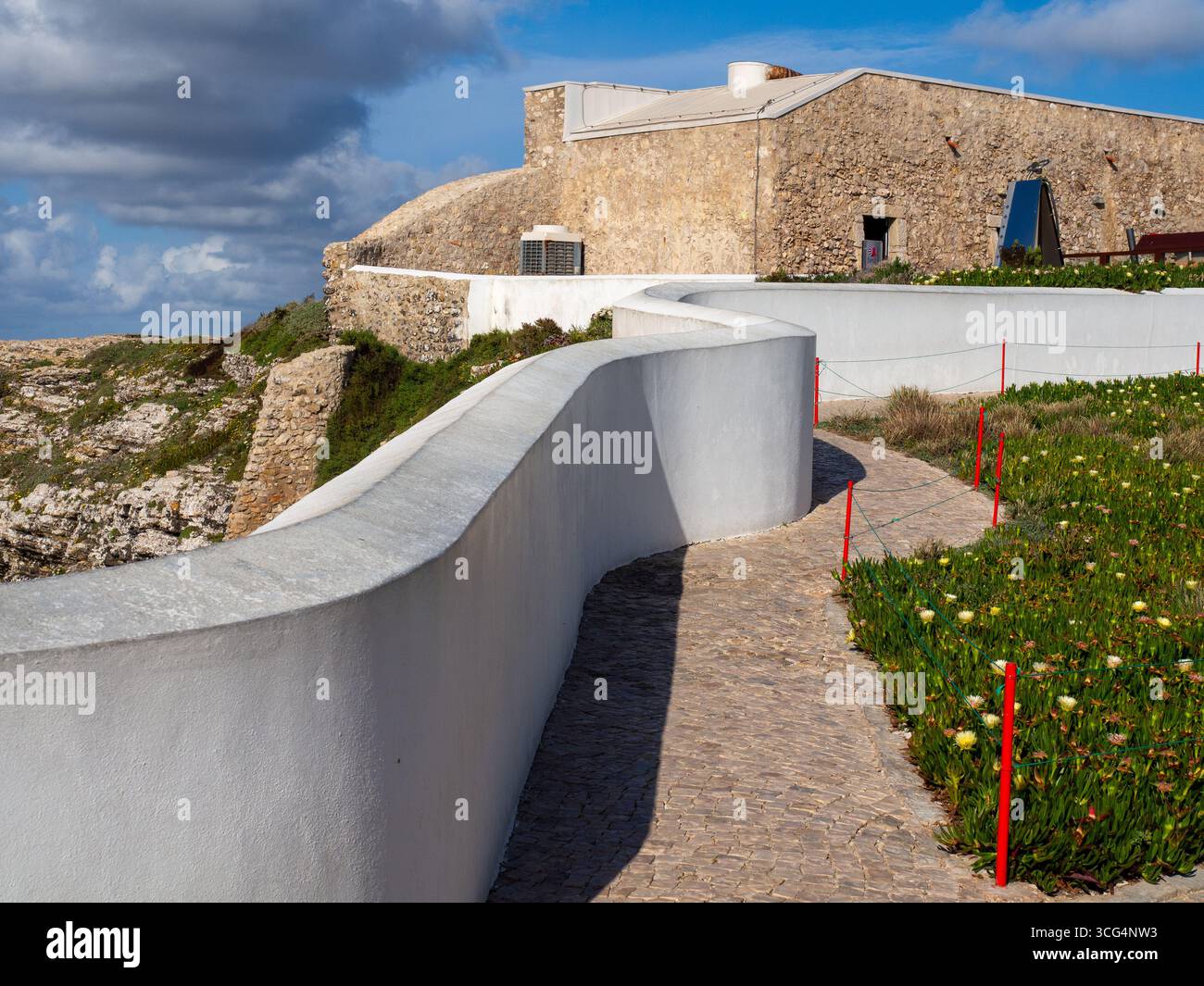 Stone fortress walls and curved white pathway at Fortaleza de Sagres ...