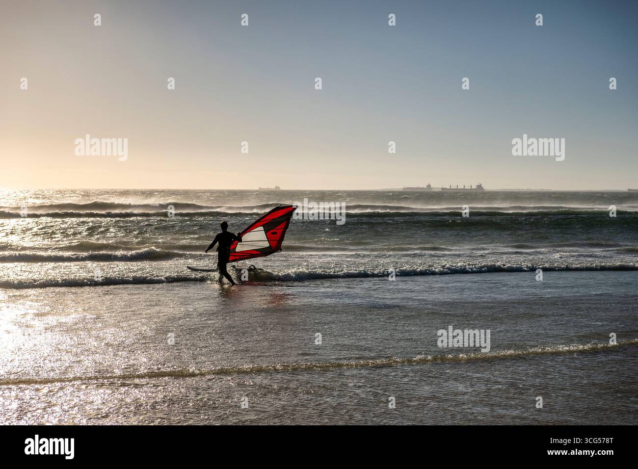 Wind surfer holding the sail and about to hit the waves on a windy day ...