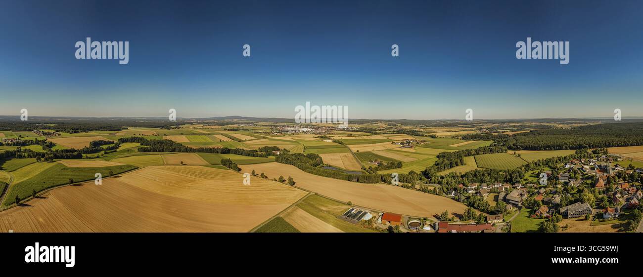 A broad landscape with rolling hills and diverse fields shows the rural ...