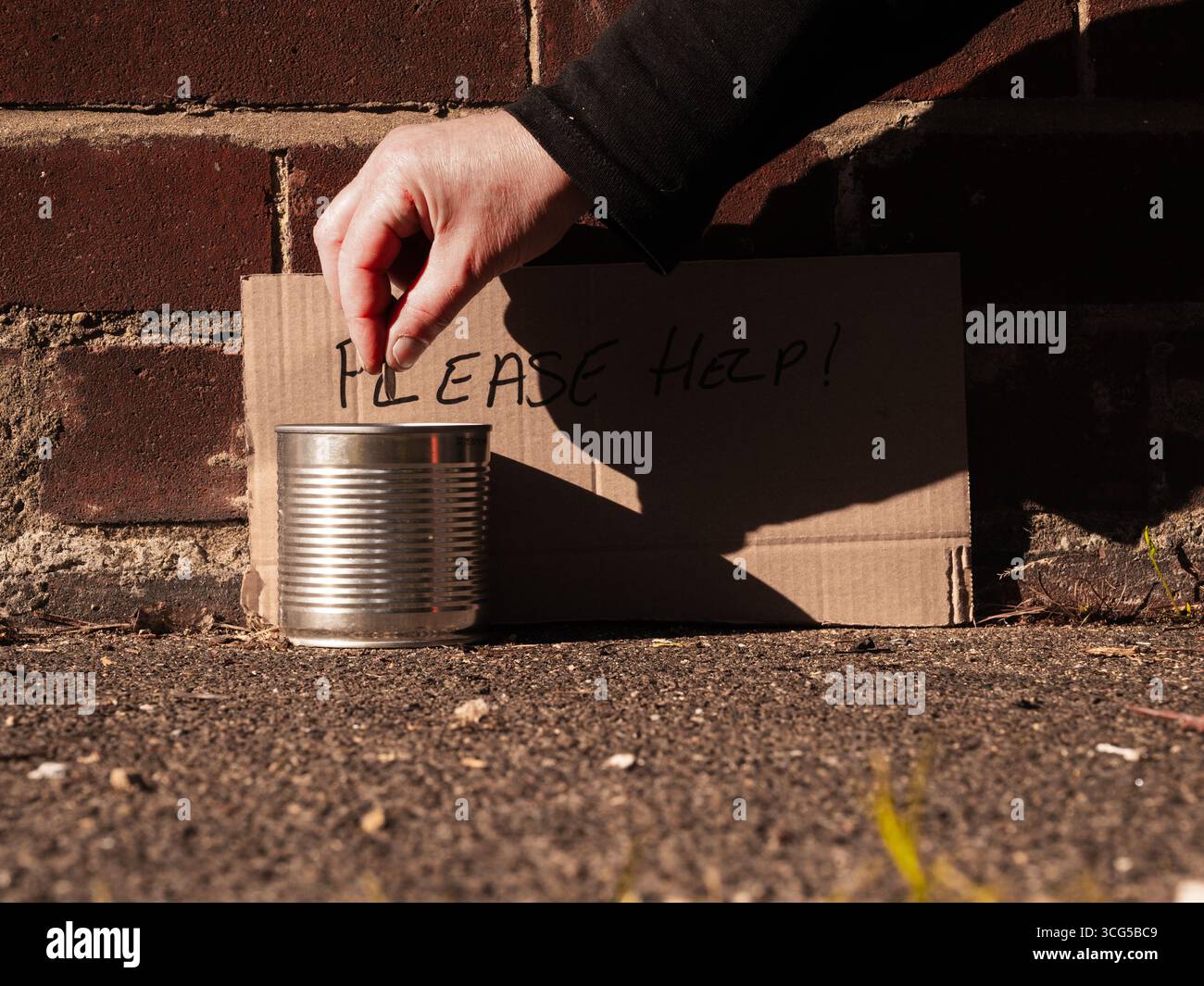 Hand putting money in charity tin Stock Photo - Alamy