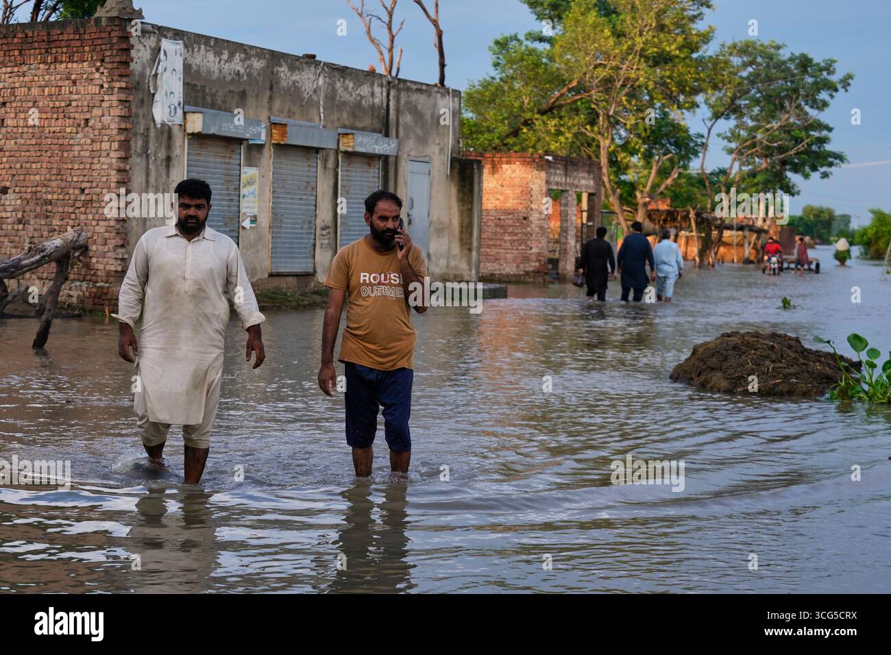 Villagers walk through a flooded area in Dhoop Sarhi village in Kasur ...