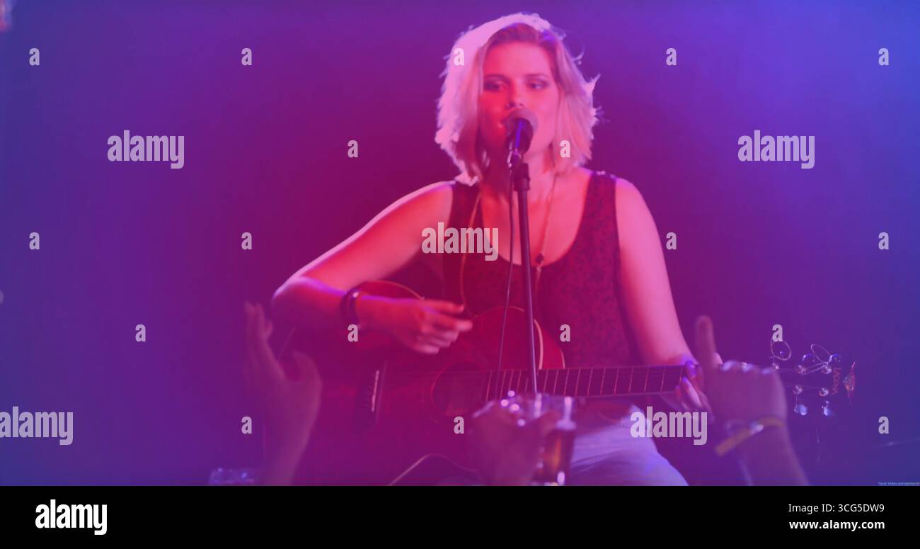 Playing acoustic guitar, teen musician singing into mic on stage, with ...