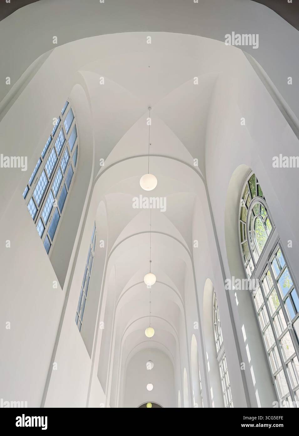 High-angle view of a stark white, modern hallway with a high vaulted ...