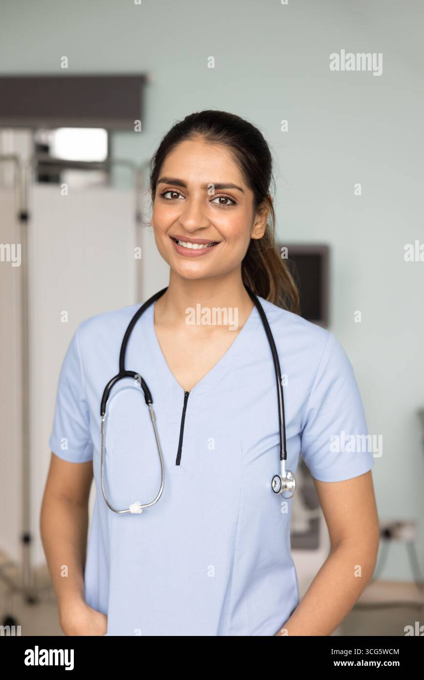 Positive Indian medical assistant woman in scrubs posing for portrait ...