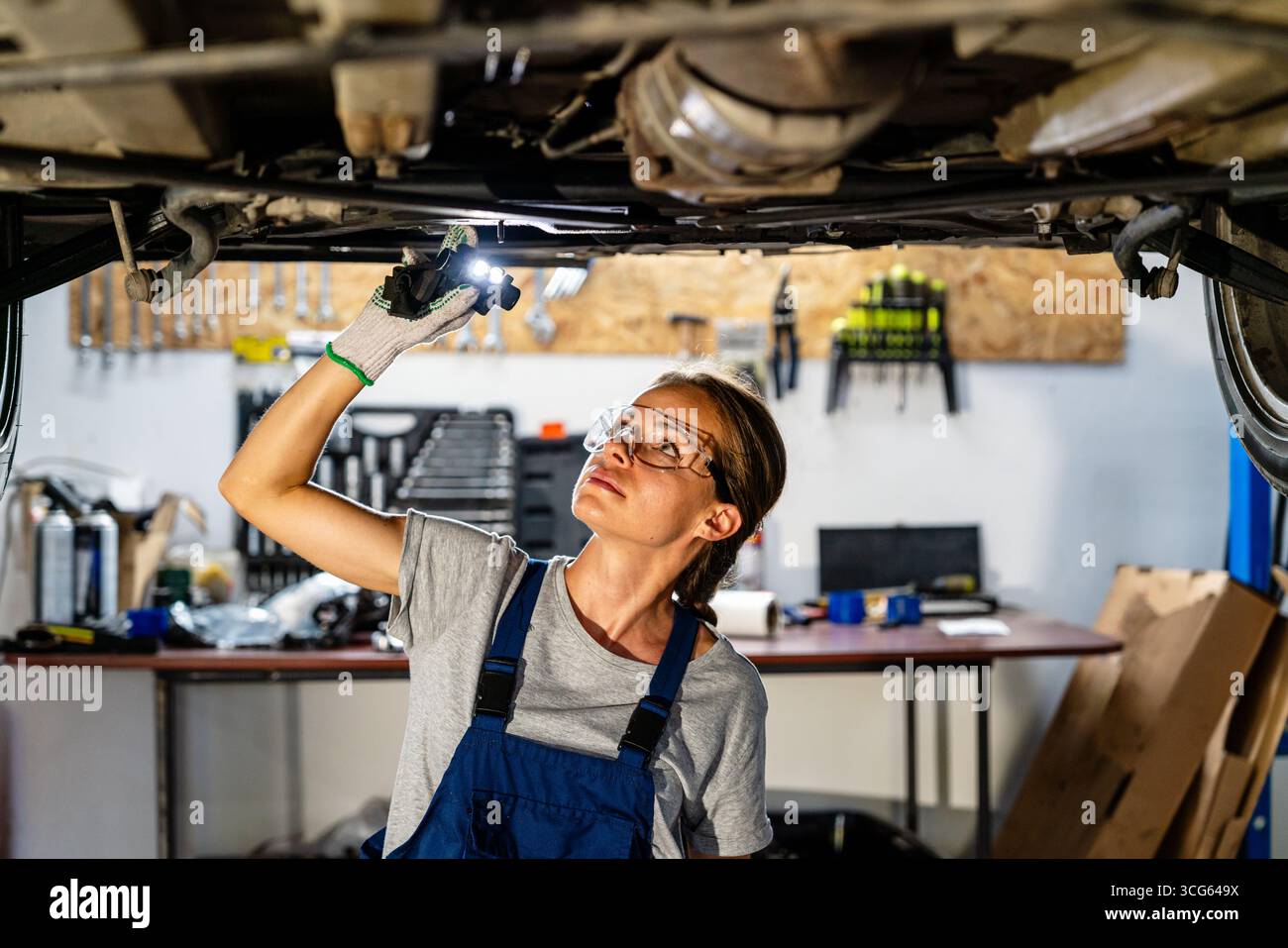 Woman car mechanic working under car in auto service garage Stock Photo ...