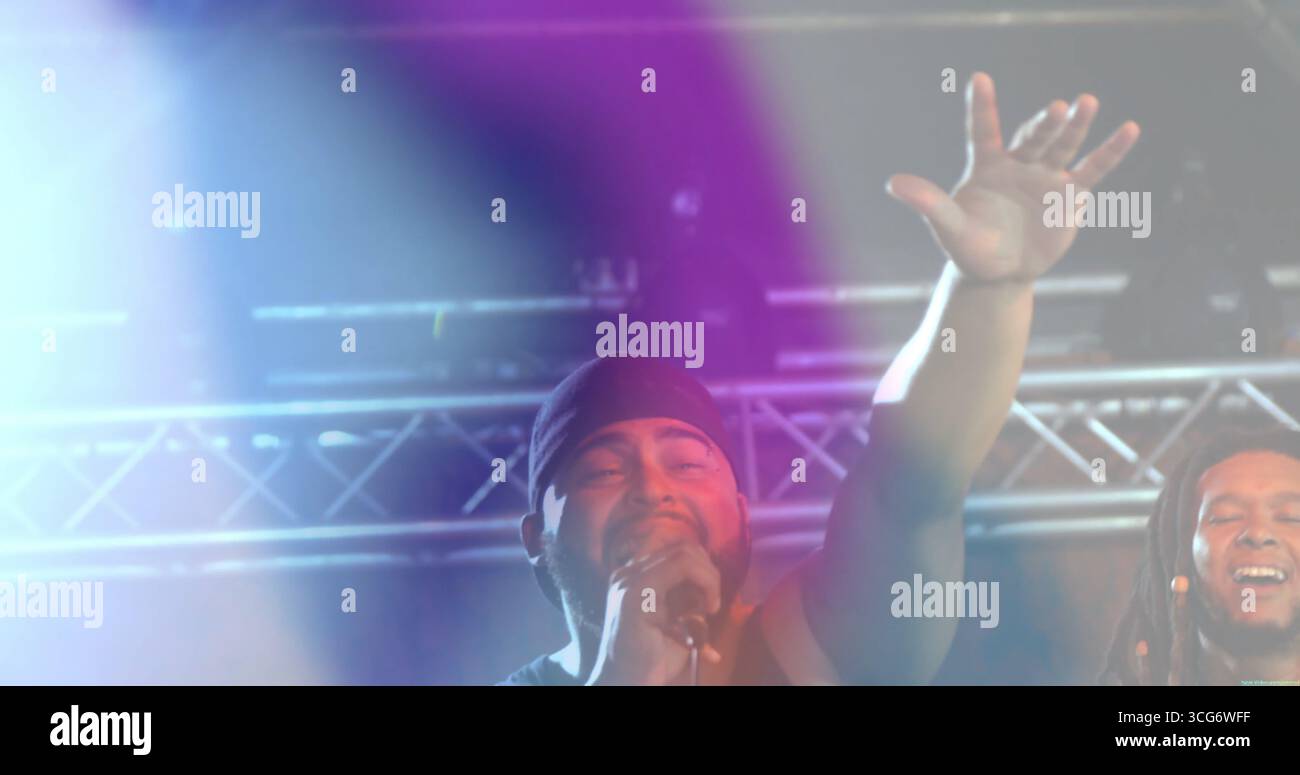 Performing male vocalist raising hand and singing with microphone on ...