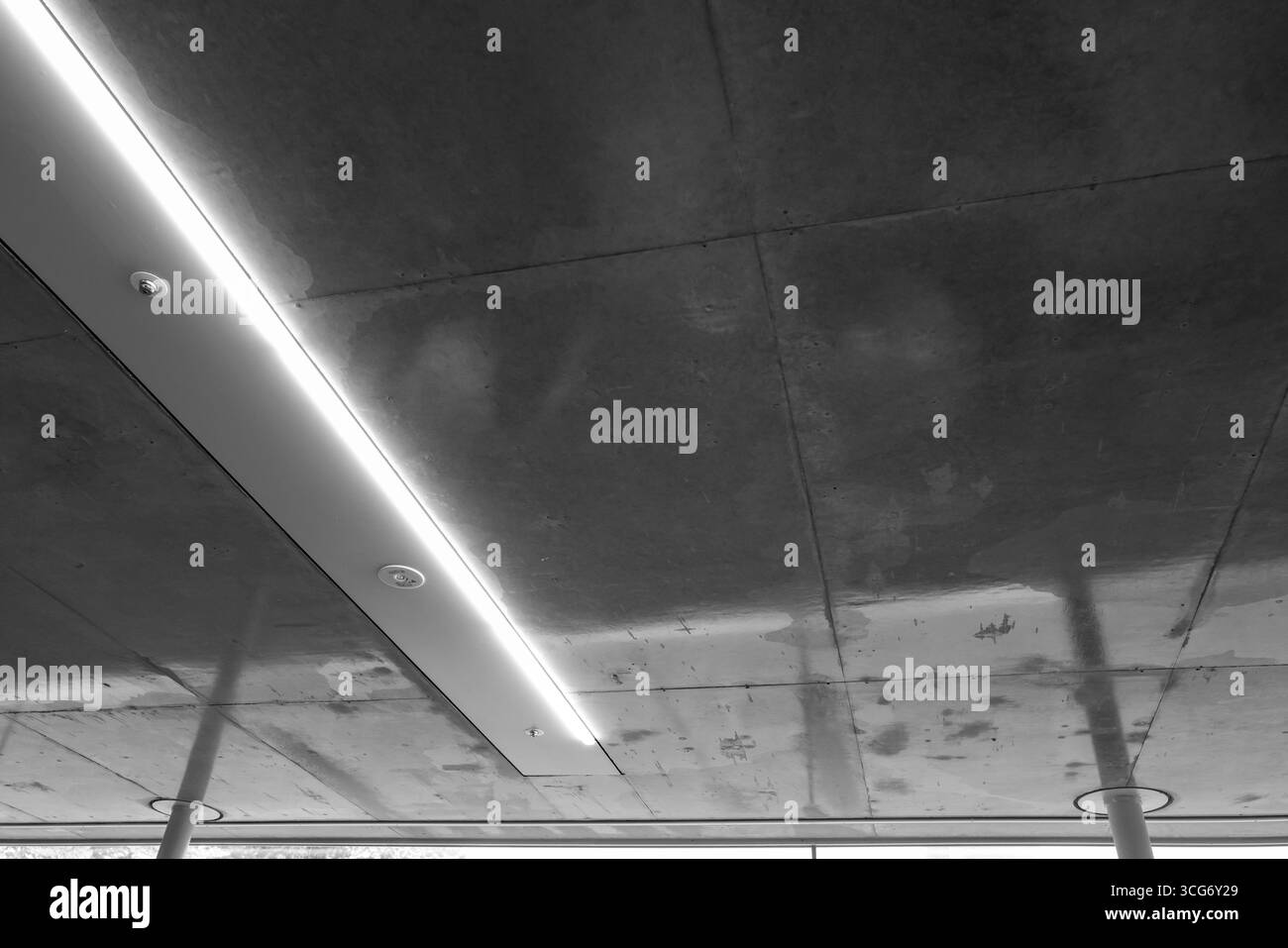 A grayscale image showcasing a modern ceiling with linear lighting and ...