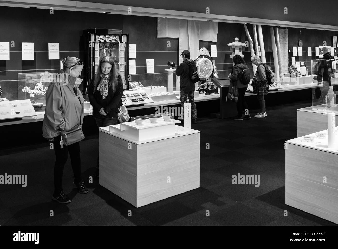 A group of people visiting a museum, interacting with displays and ...