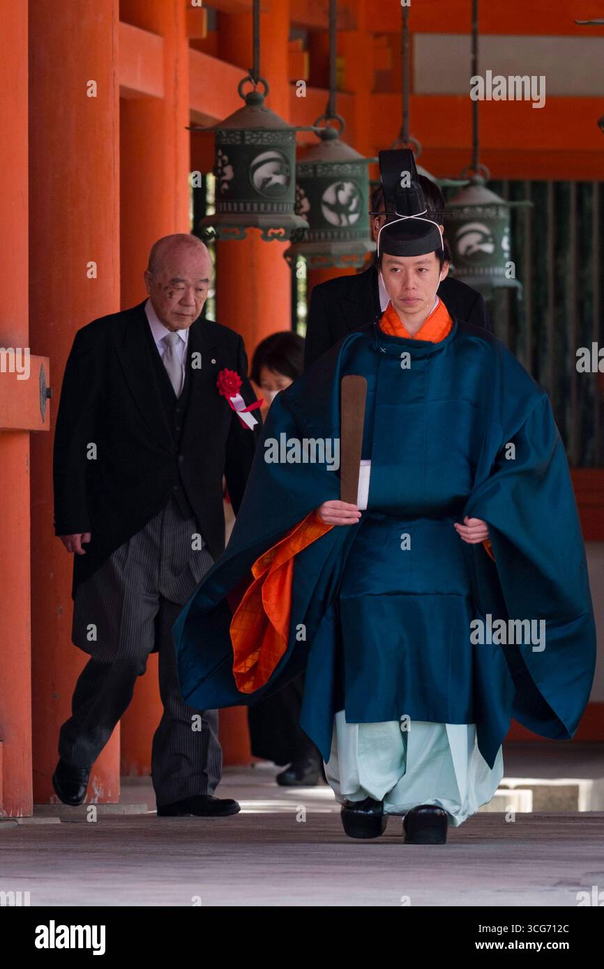 Shinto priest wearing blue shōzoku vestments while holding a baton ...