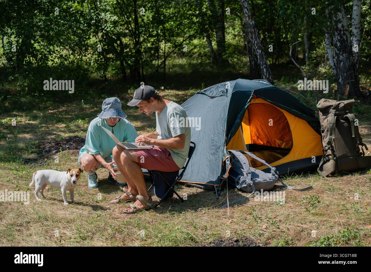 Caucasian man working on laptop in camping. Couple relaxing in nature ...