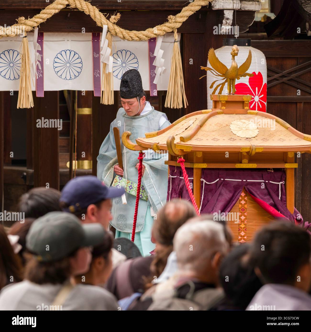 Shinto priest performing rite standing behind the Mikoshi sacred ...