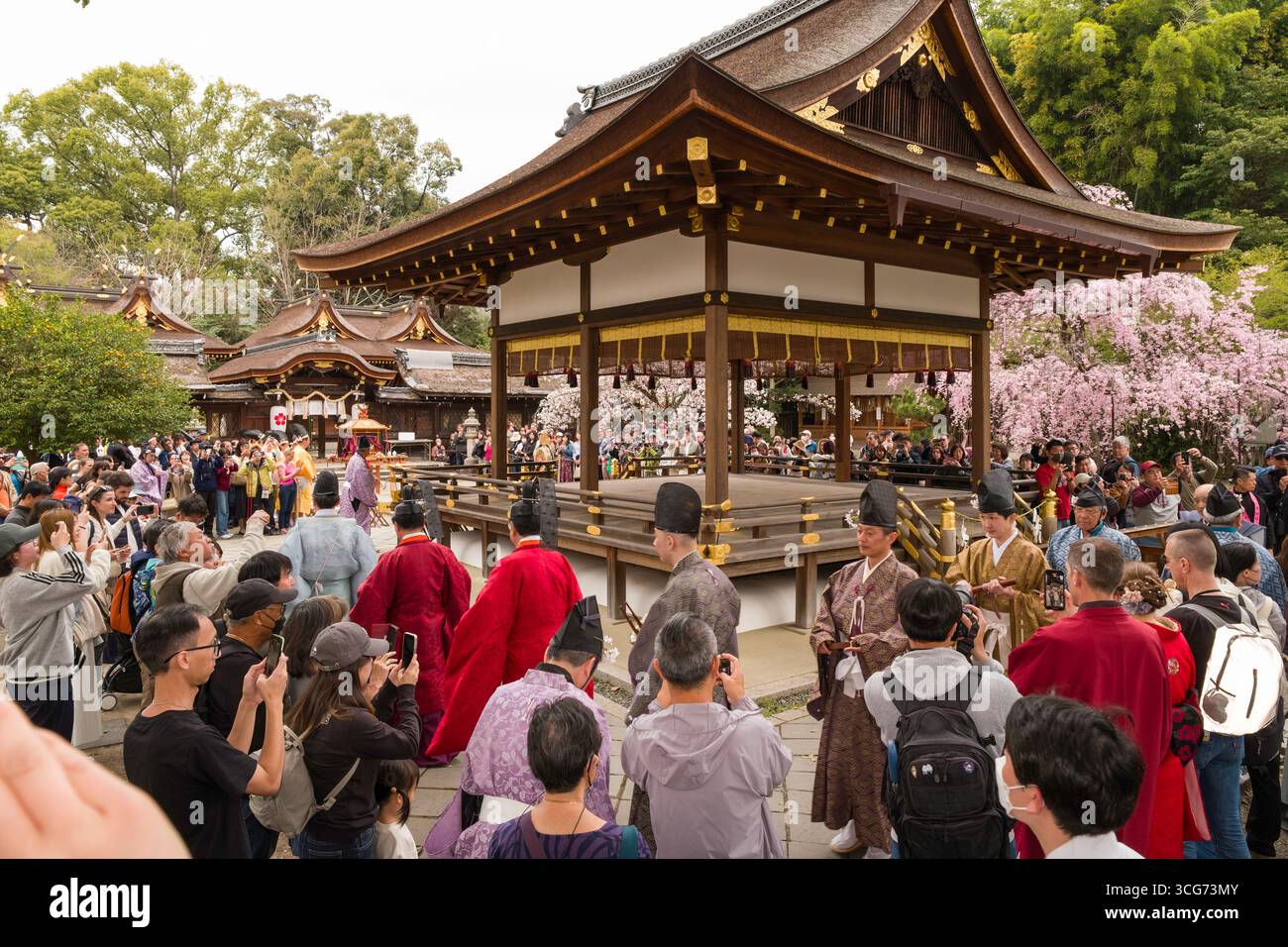 Spectators watching procession of Shinto priest and dignitaries around ...