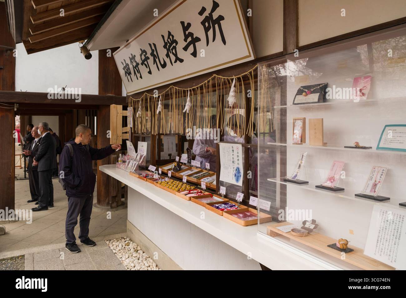 A male customer examines shrine goods for sale at Hirano Shrine in ...