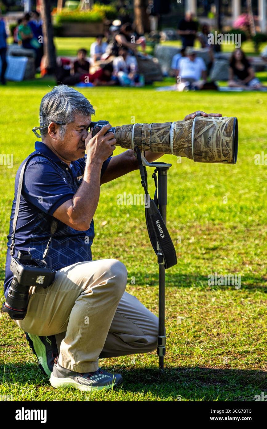 Photographer using long, powerful zoom lens with monopod, Lumphini Park ...