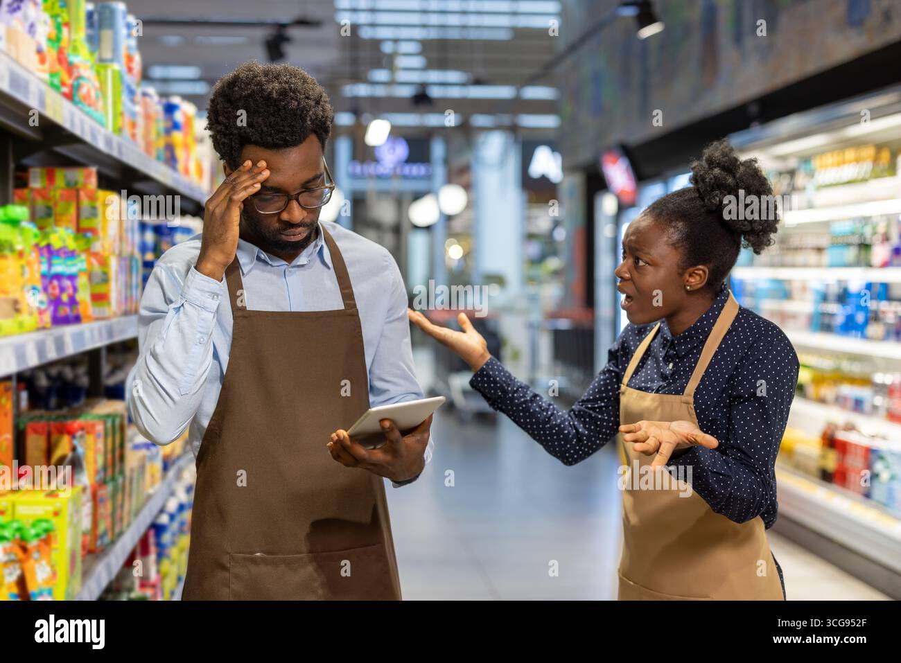 Two supermarket employees, wearing uniforms, having a disagreement in ...