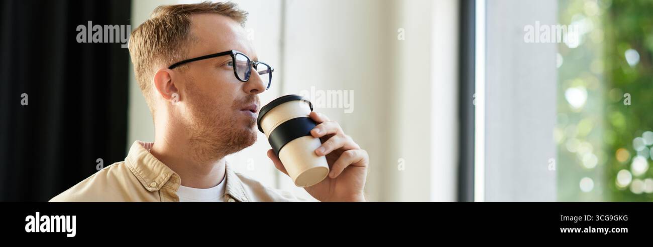 A young professional sips coffee, reflecting on his work in a bright ...