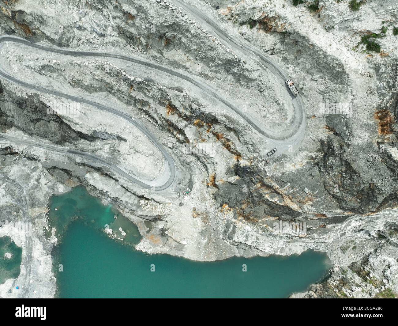 Aerial view truck in motion through terraced quarry levels during stone ...