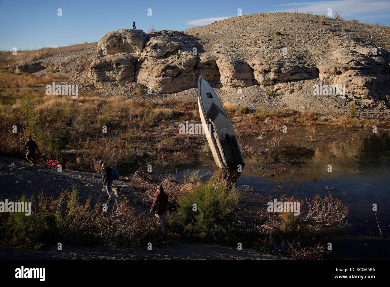 FILE - People walk by a formerly sunken boat standing upright along the ...