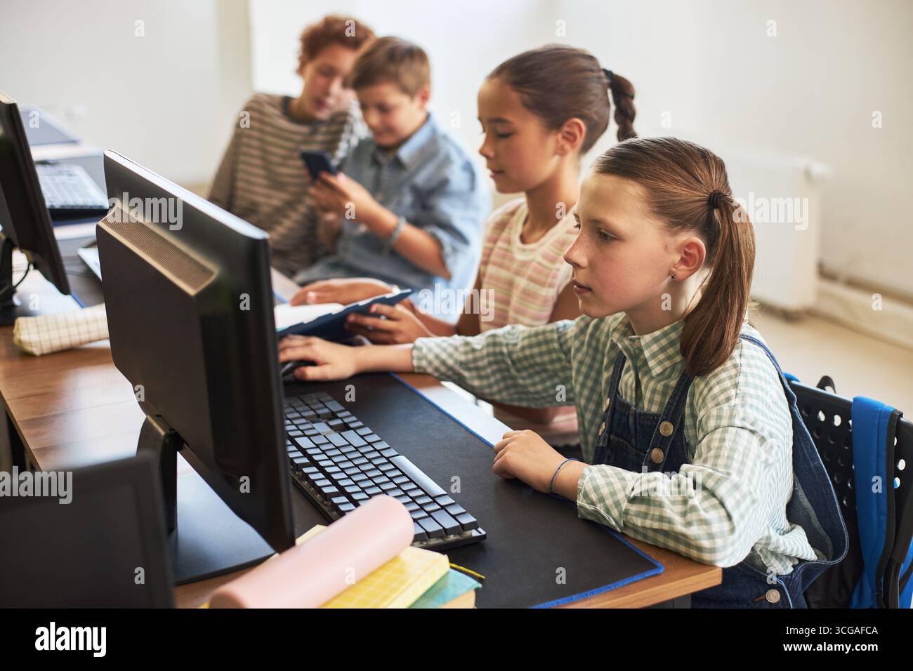Group of Caucasian and multiethnic children sitting at desk using ...