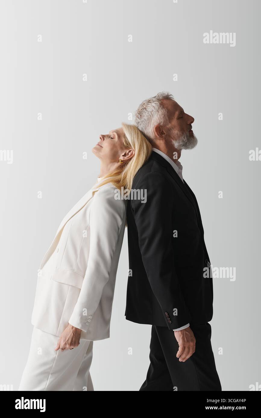 A stylish senior couple leans back to back, showcasing their love and ...