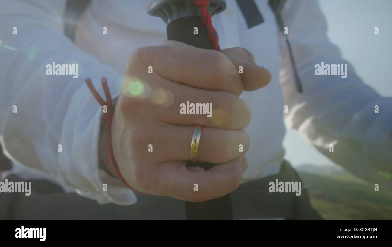 Detailed view of a hand with a wedding ring gripping trekking poles ...