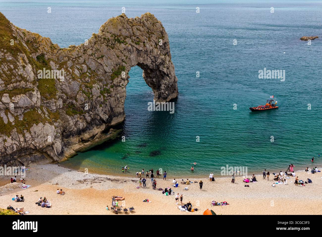 Holidaymakers swimming and relaxing on the beach by the iconic Durdle ...