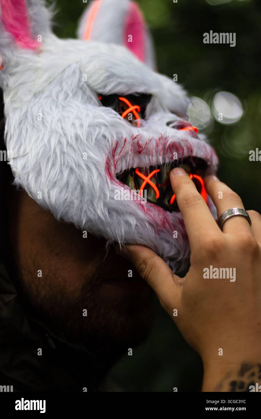 Creepy Halloween mask with red LED eyes held by a figure in a haunted ...