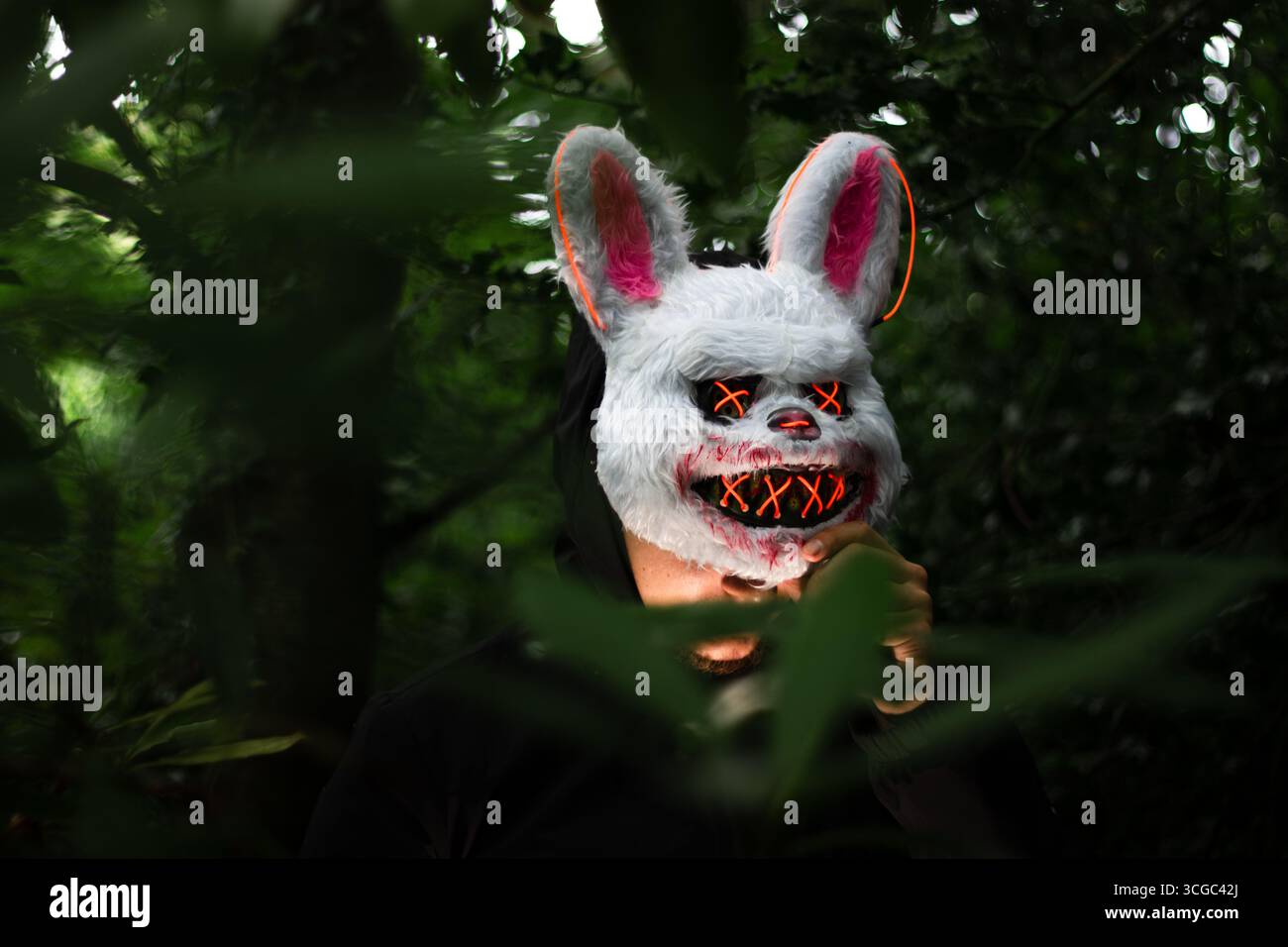 Creepy Halloween mask with red LED eyes held by a figure in a haunted ...