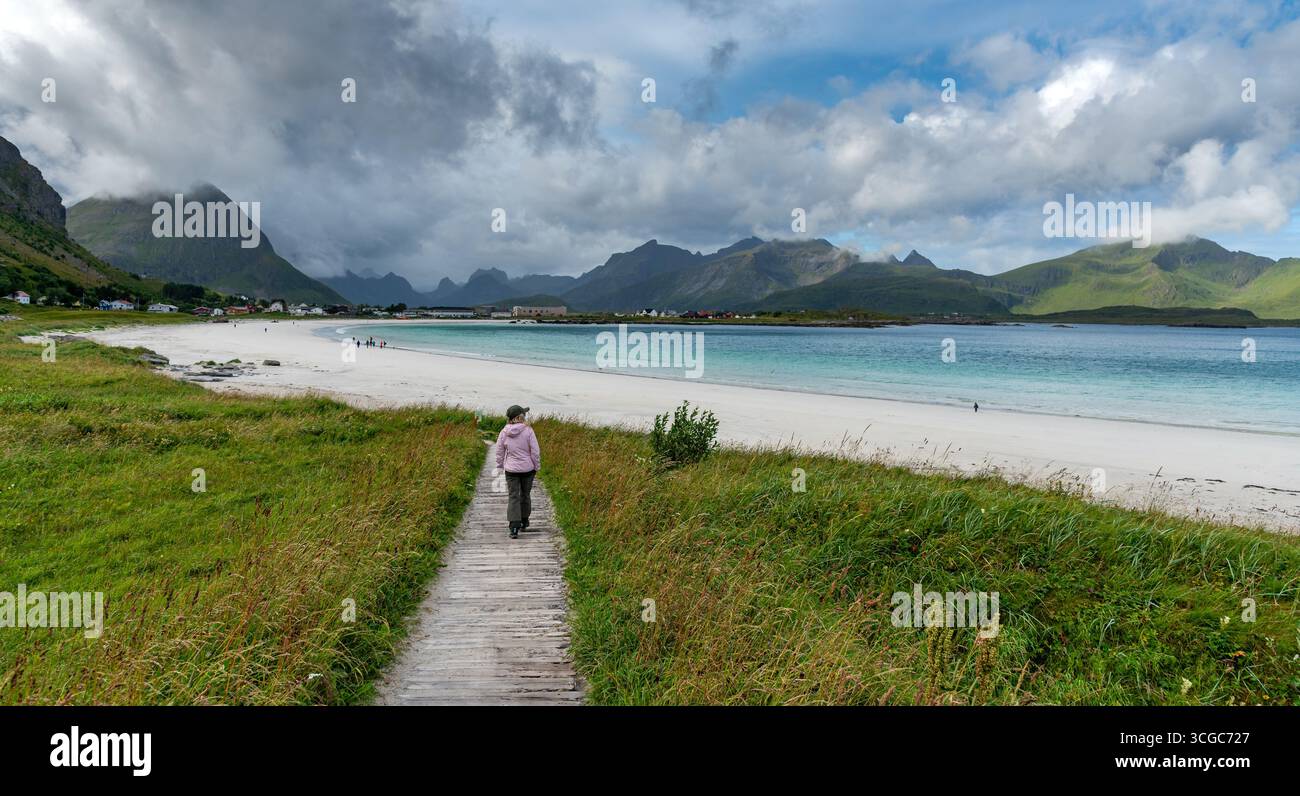 Tourist enjoying ramberg beach in lofoten islands, norway, on a cloudy ...