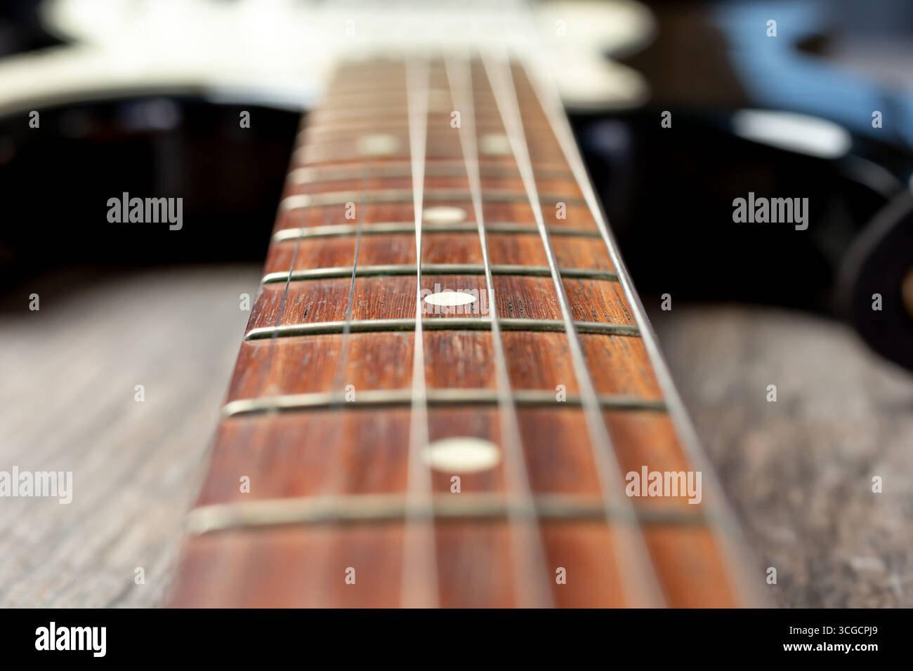 A closeup view of the fretboard of a black and white electric guitar ...