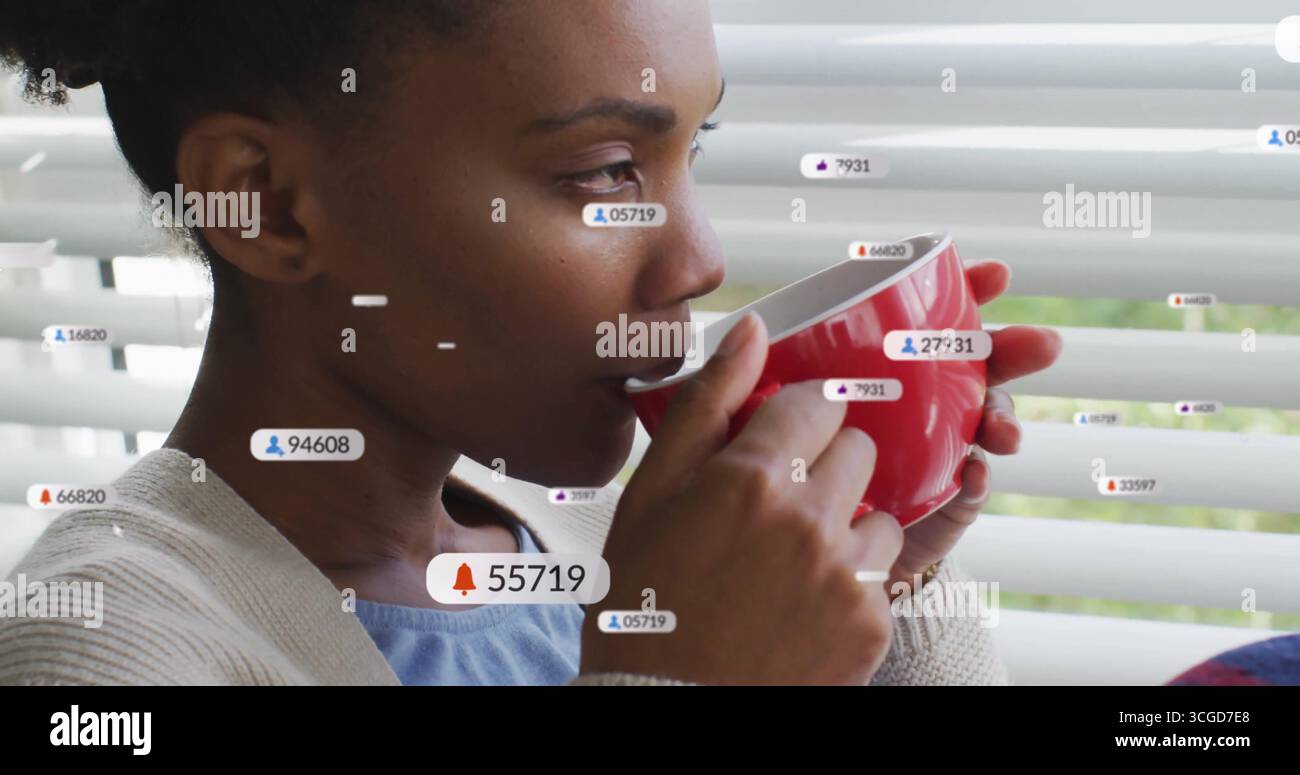 Sipping woman holding red mug near window blinds at home, with floating ...