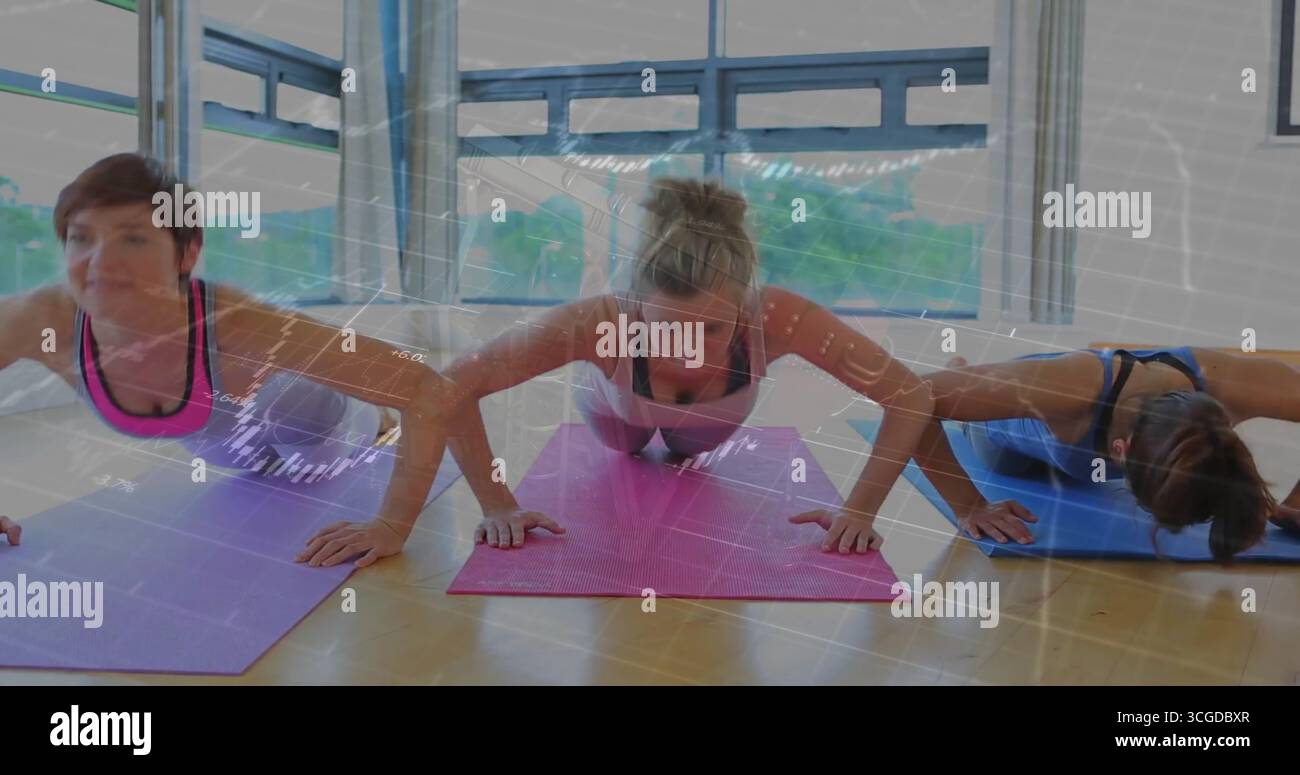 Three women performing push-ups on yoga mats inside fitness studio ...