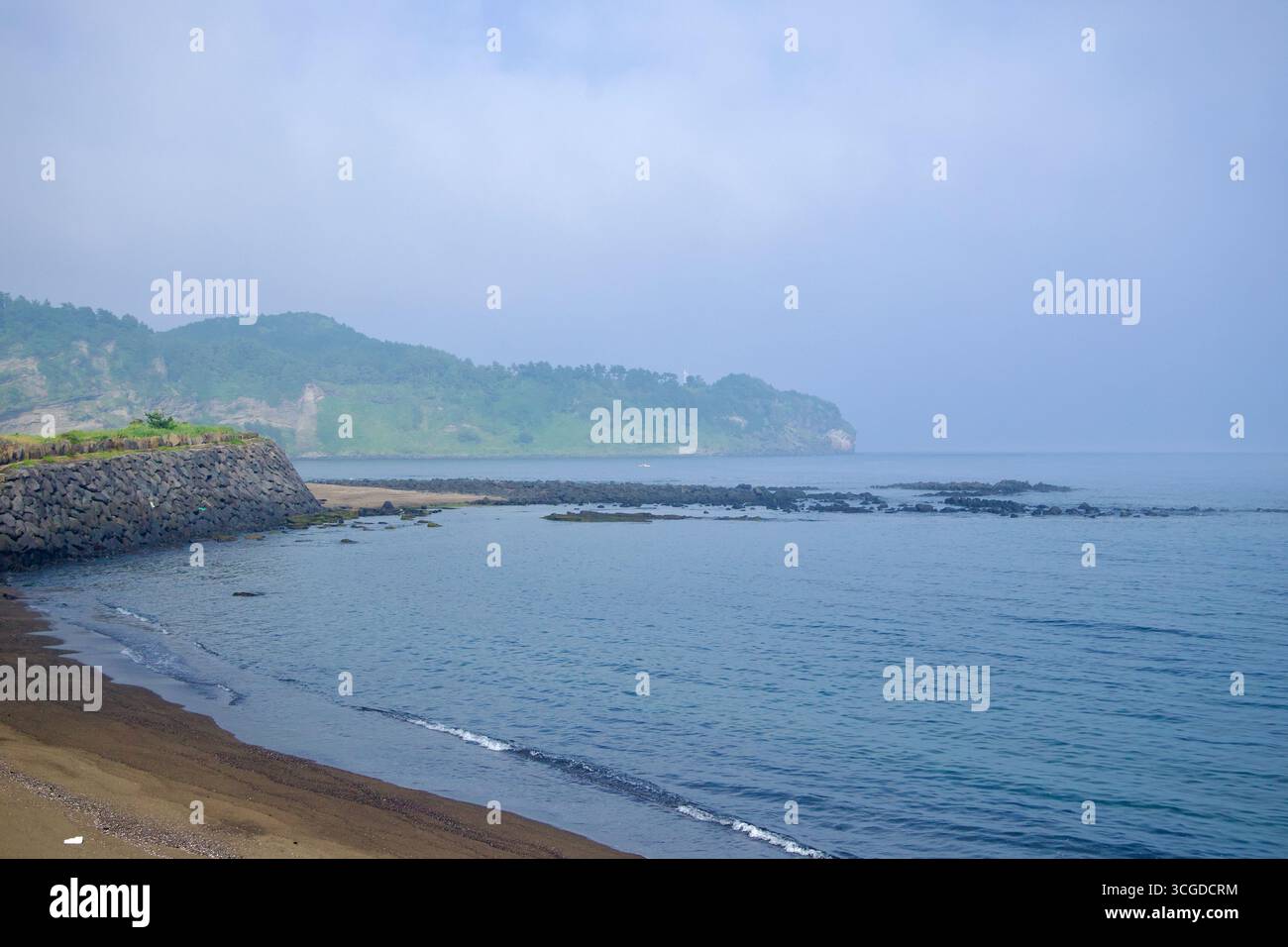A small sandy cove, basalt reefs and a low breakwater line the bay ...