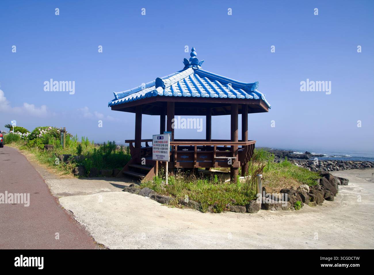 A small wooden pavilion with a bright blue tiled roof stands at the ...